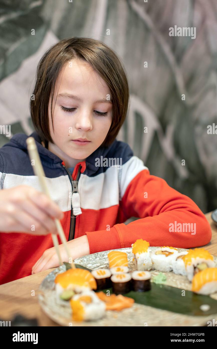 Child, eating japanese sushi and noodles with chopsticks in a ...