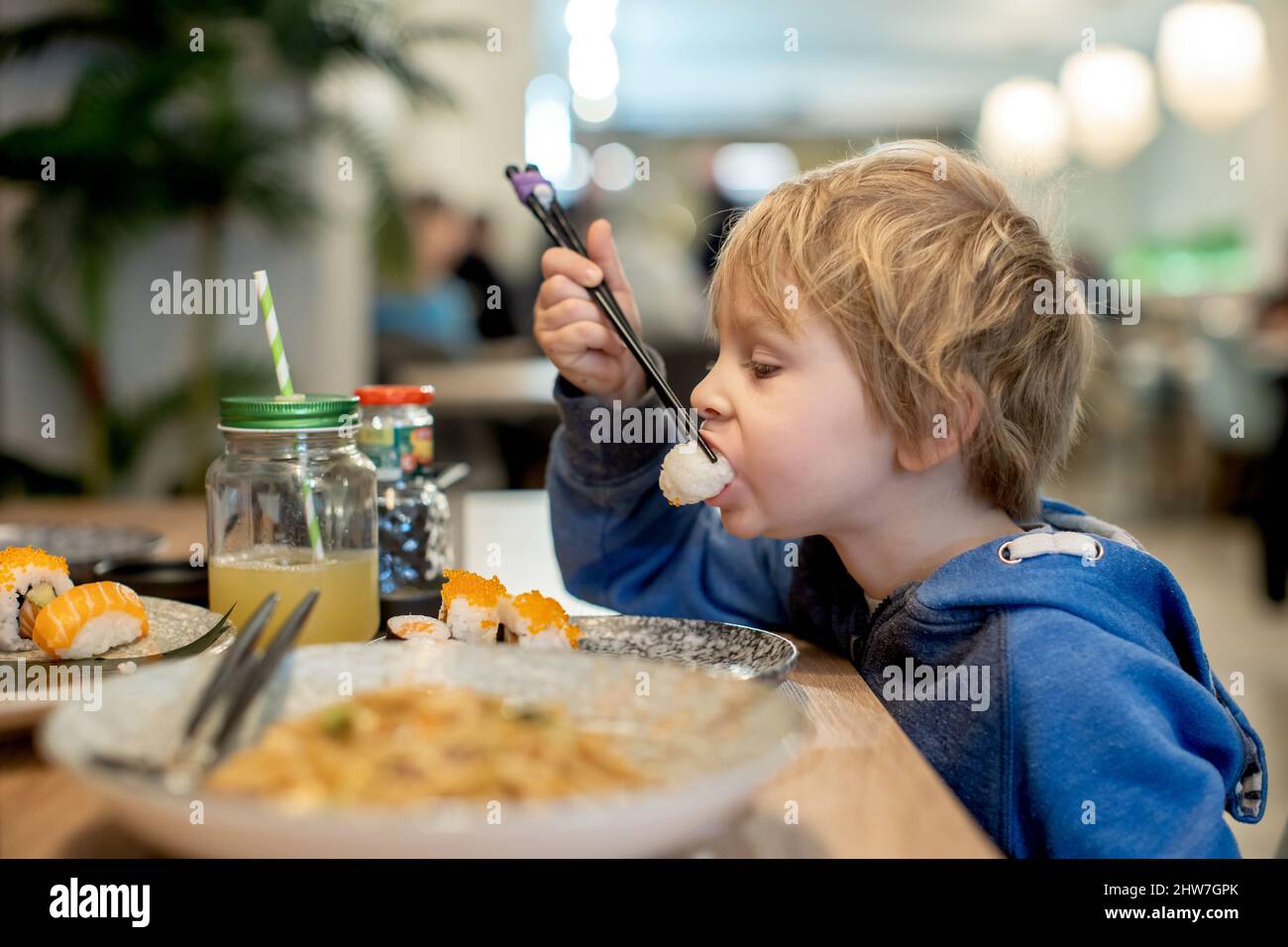 Child, eating japanese sushi and noodles with chopsticks in a ...
