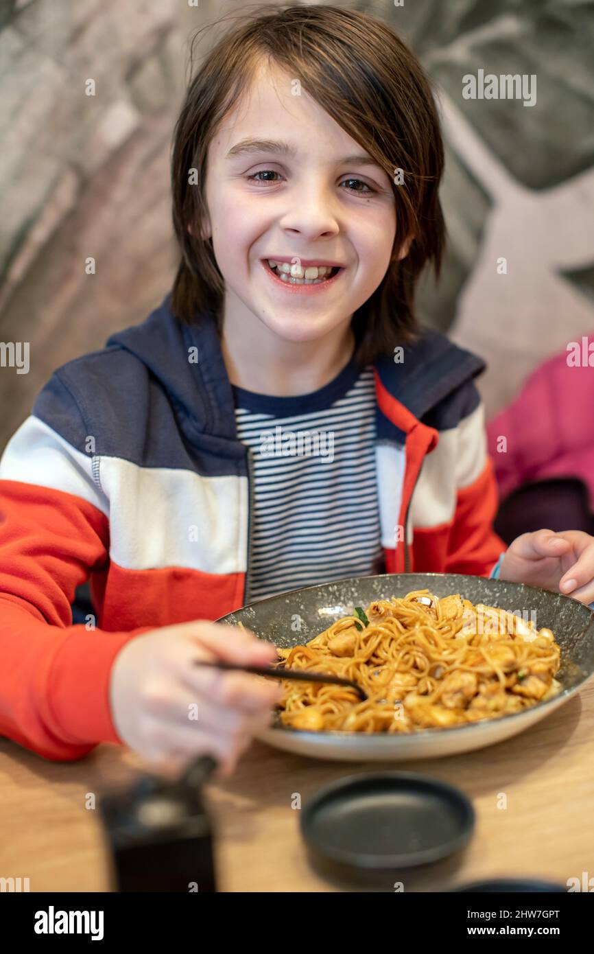 Child, eating japanese sushi and noodles with chopsticks in a restaurant, dinnertime Stock Photo ...