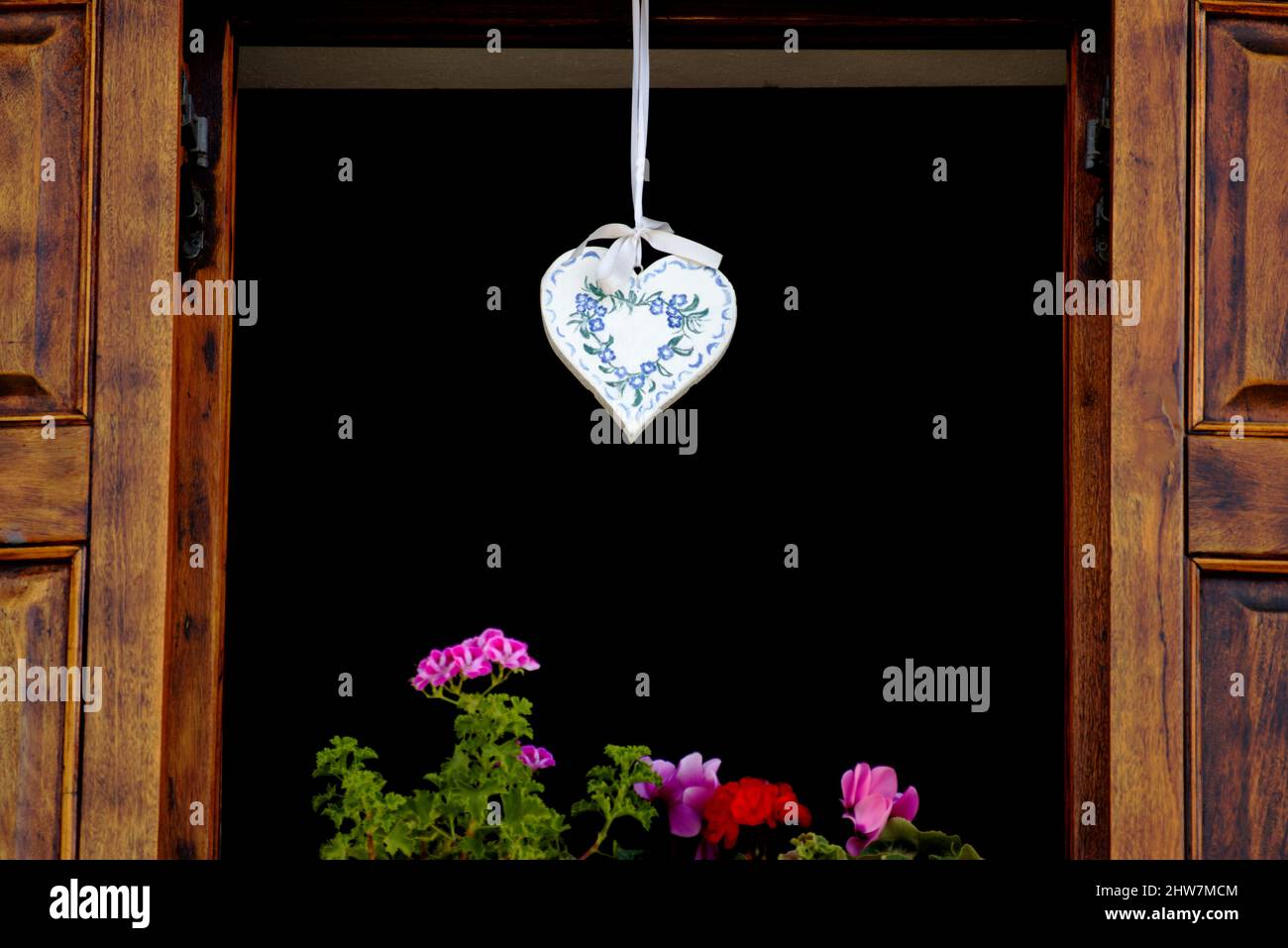 Open wooden window with shutters and flowers with white heart shaped ...