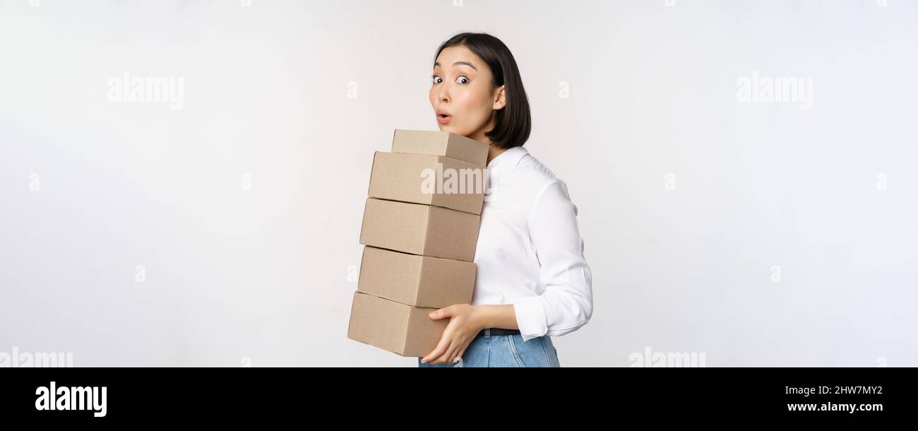 Portrait of young asian woman holding boxes, carry delivery goods ...