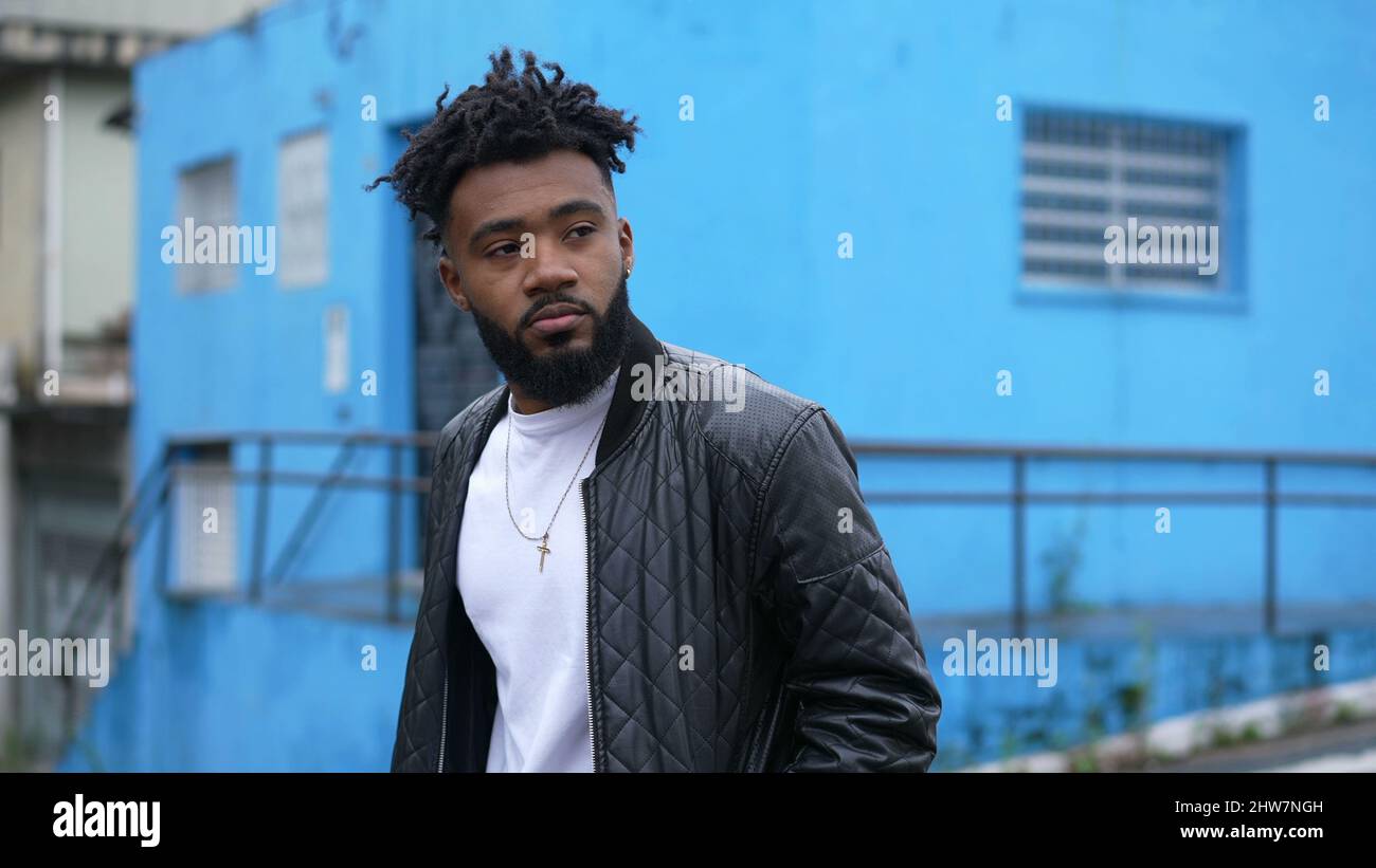 A pensive young black man walking outside in urban street a thoughtful ...