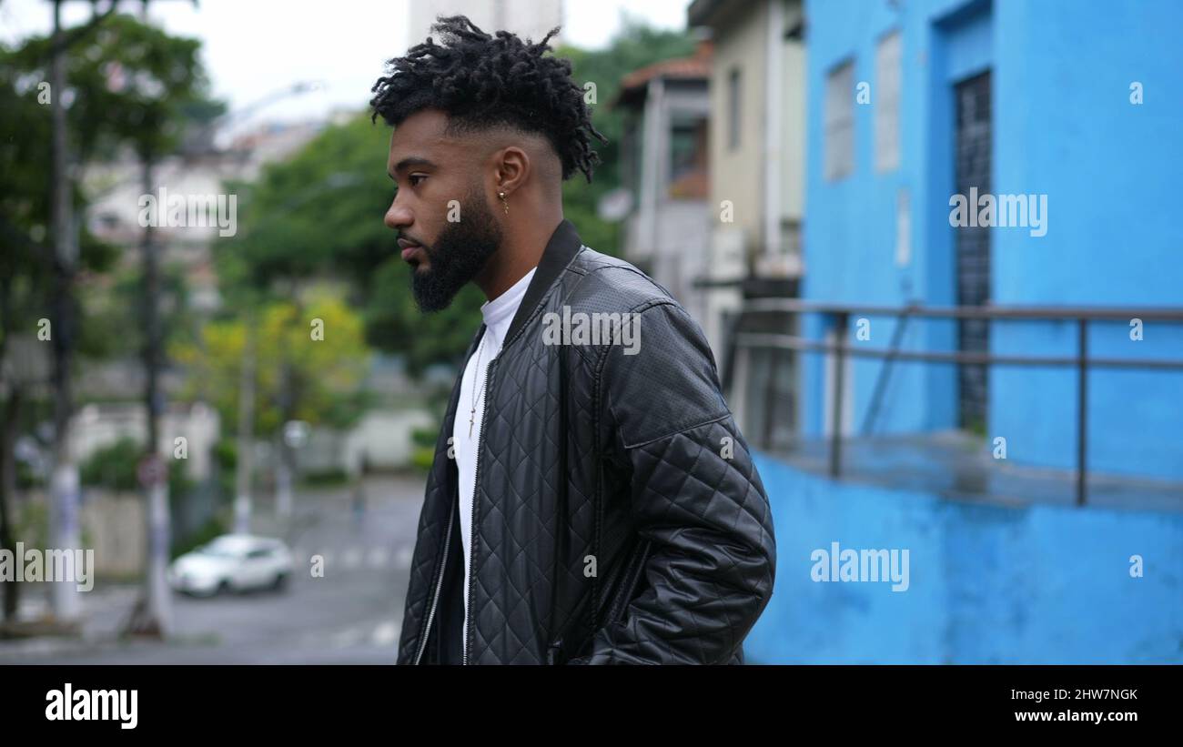 A pensive young black man walking outside in urban street a thoughtful ...