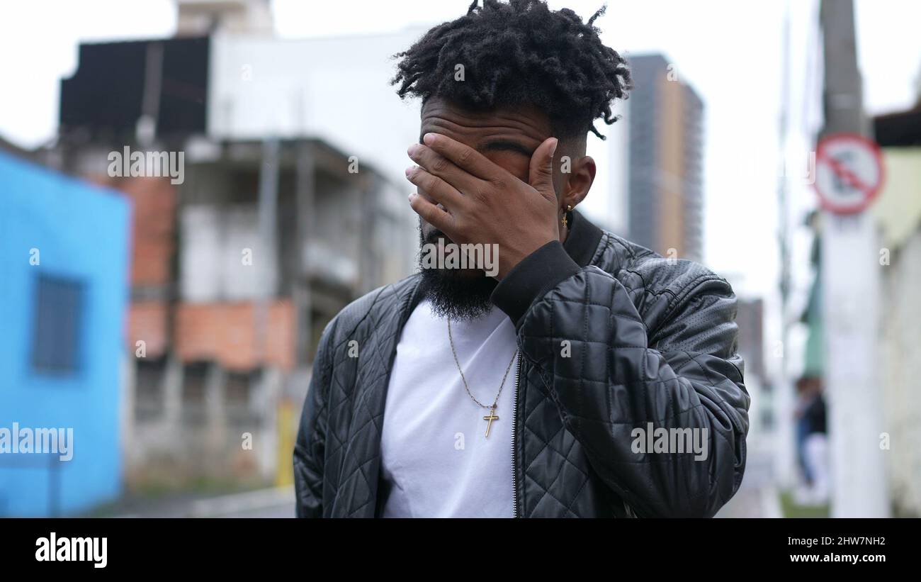A pensive young black man walking outside in urban street a thoughtful ...