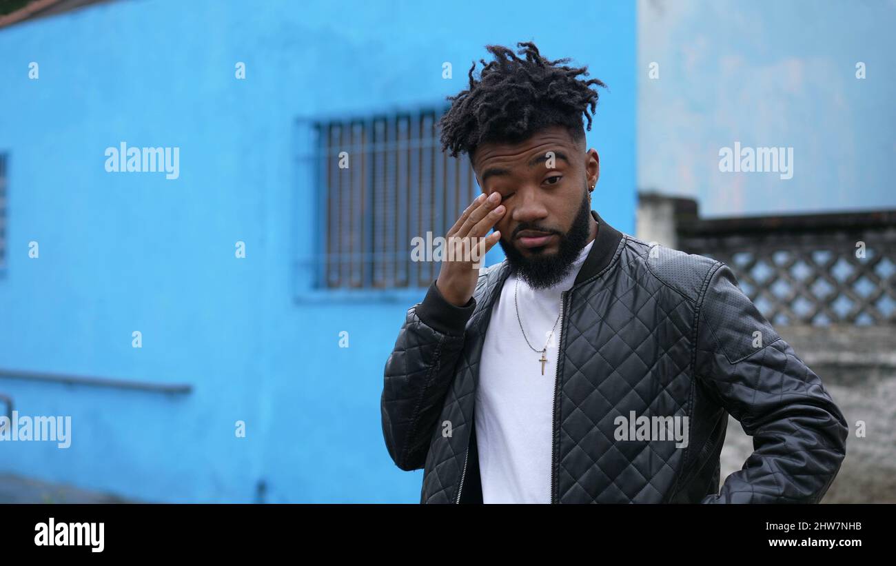 A tired black man rubbing eye and face outside Stock Photo - Alamy
