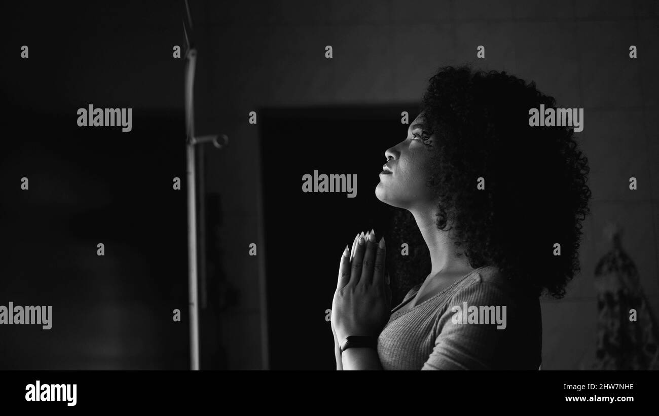 A woman praying at home by window having HOPE and FAITH in monochrome ...