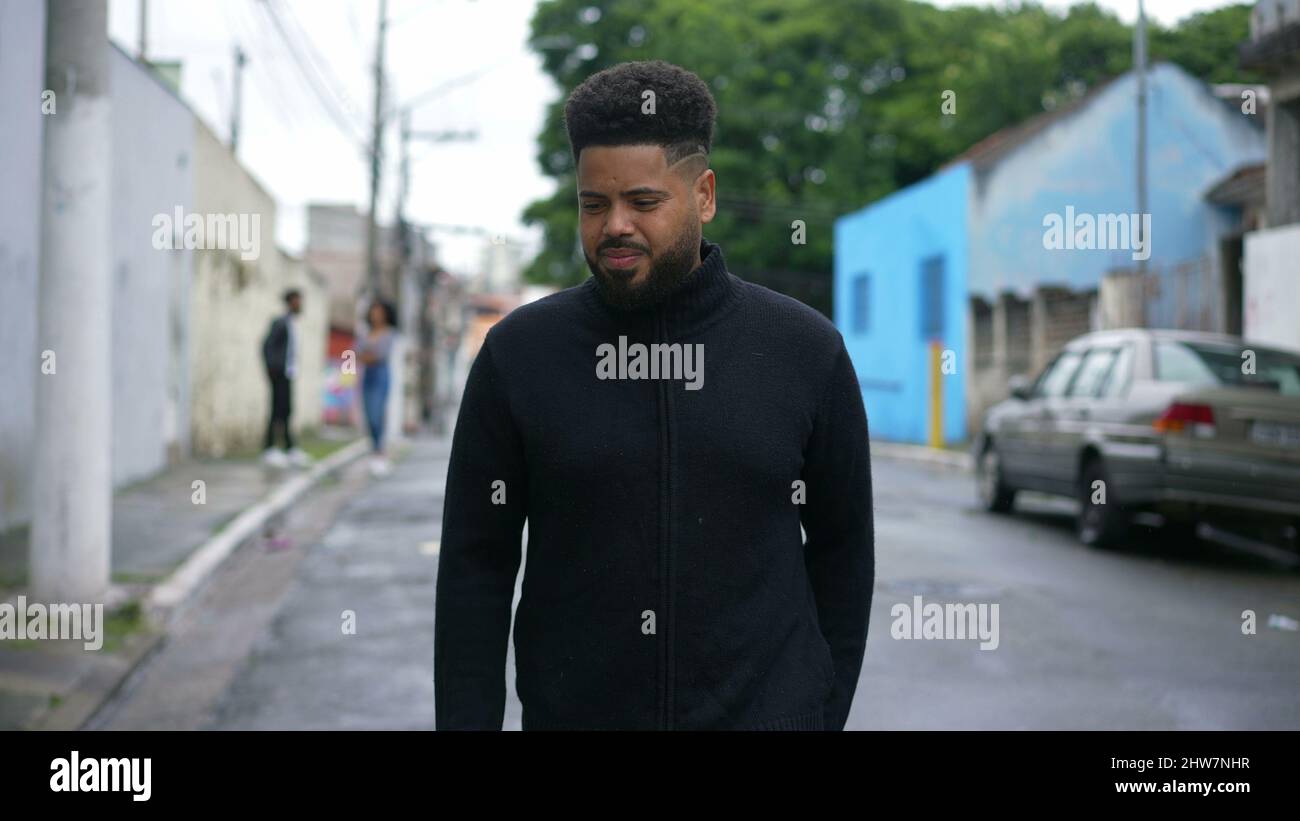 A pensive young man walking in urban street tracking shot Stock Photo ...