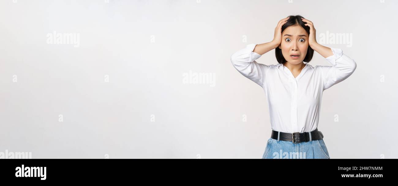 Image of shocked anxious asian woman in panic, holding hands on head ...