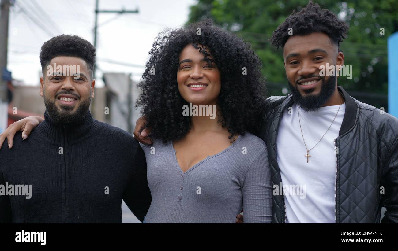 Three friends posing for camera outside in urban street Stock Photo - Alamy