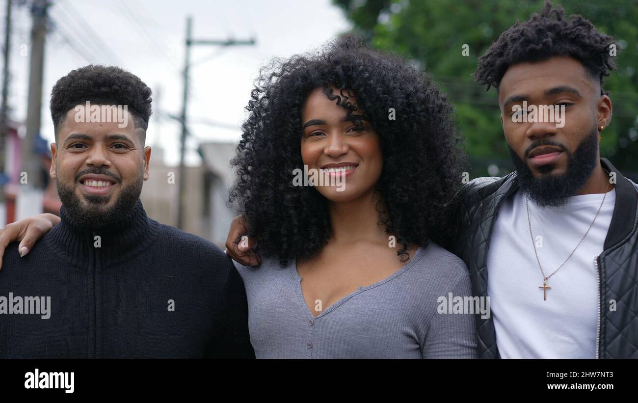 Three friends posing for camera outside in urban street Stock Photo - Alamy
