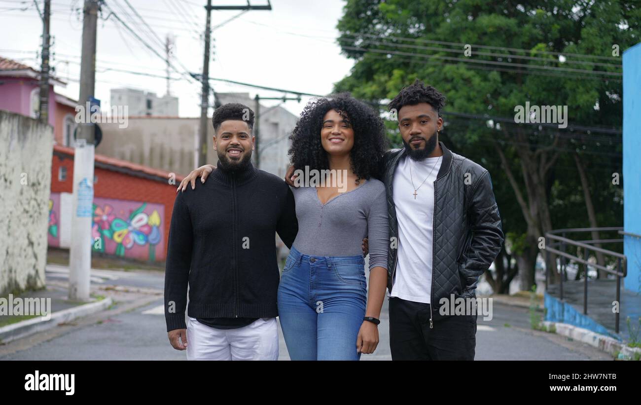 Three friends posing for camera outside in urban street Stock Photo - Alamy