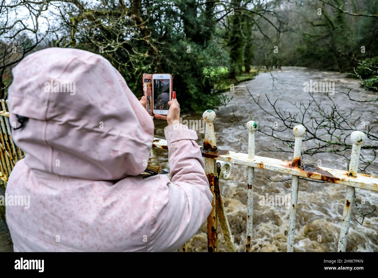 Flood tourist stood on a foot bridge photographing storm swollen River ...