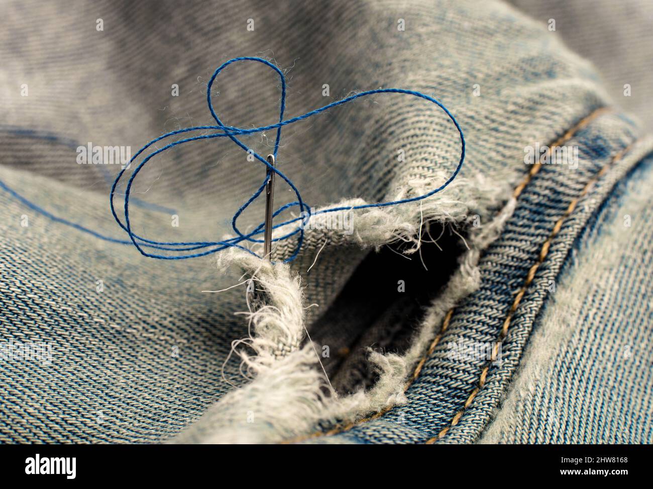 Hole in jeans. Needle with thread for darning jeans. Tools for work ...