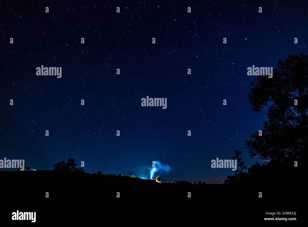 Smoke in the countryside on a hill against a starry sky, silhouettes of ...