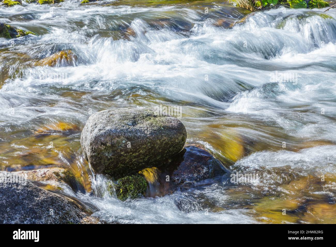 Stone in flowing river, long exposure blurred water Stock Photo - Alamy
