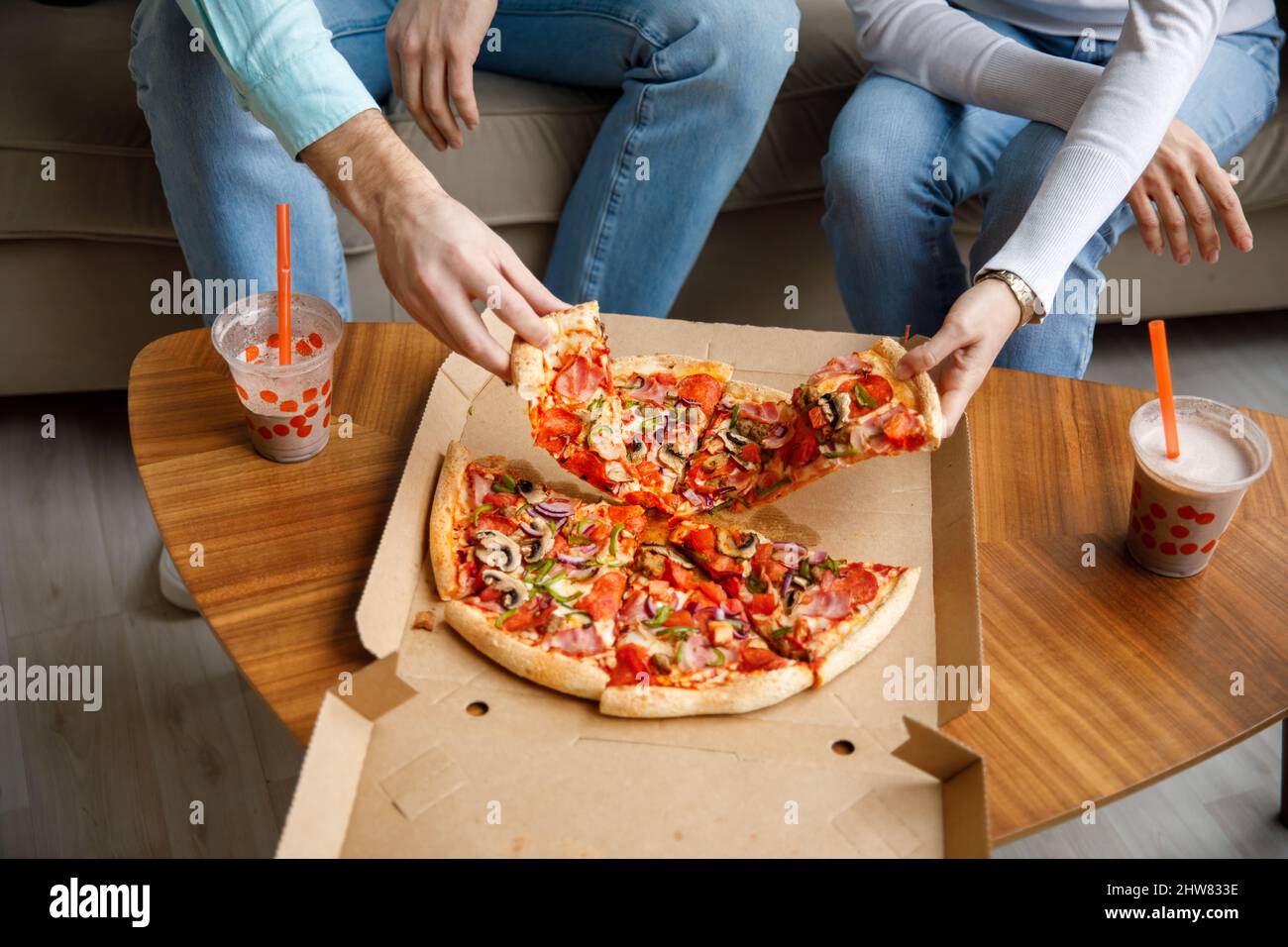Couple sharing pizza and eating Stock Photo - Alamy