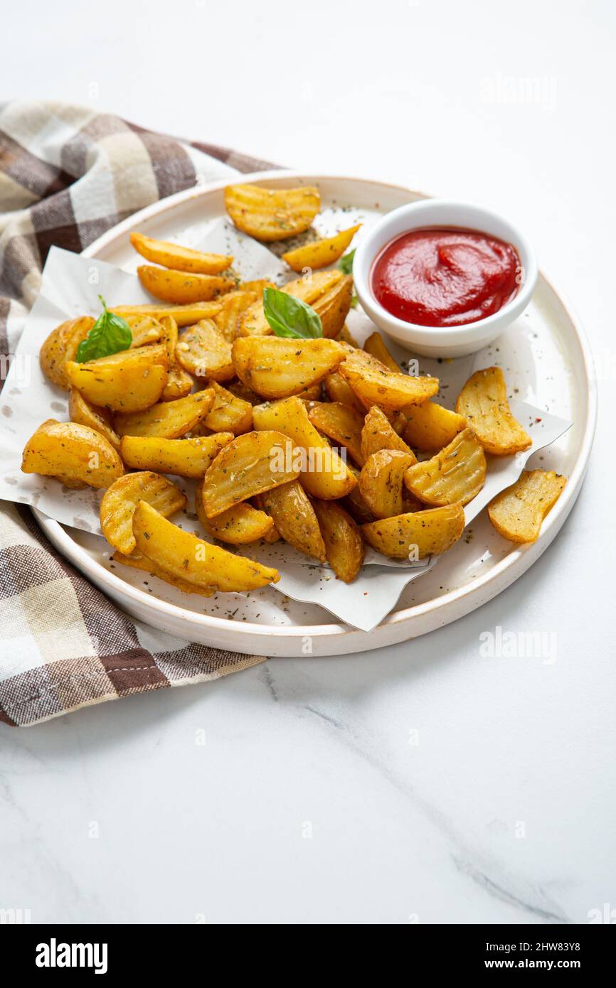 Crispy baked potatoes and ketchup on plate Stock Photo - Alamy