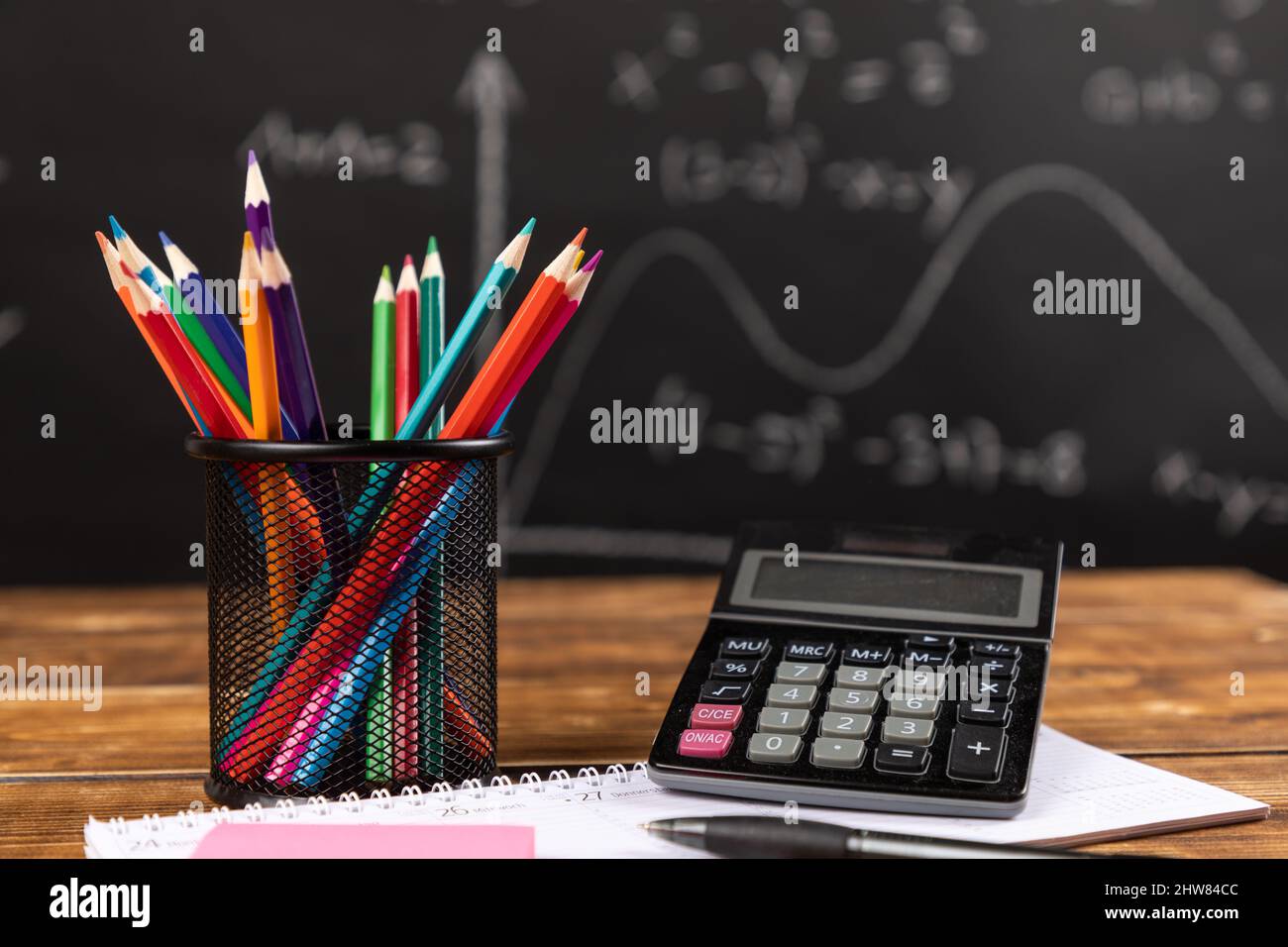 Stack of colored pencils with calculator and chalkboard Stock Photo - Alamy