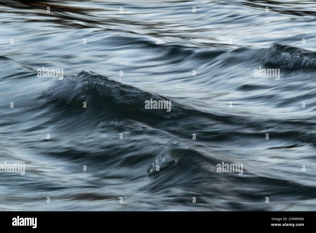 Abstract landscape of wavy turbulent water in wind with silky surface ...