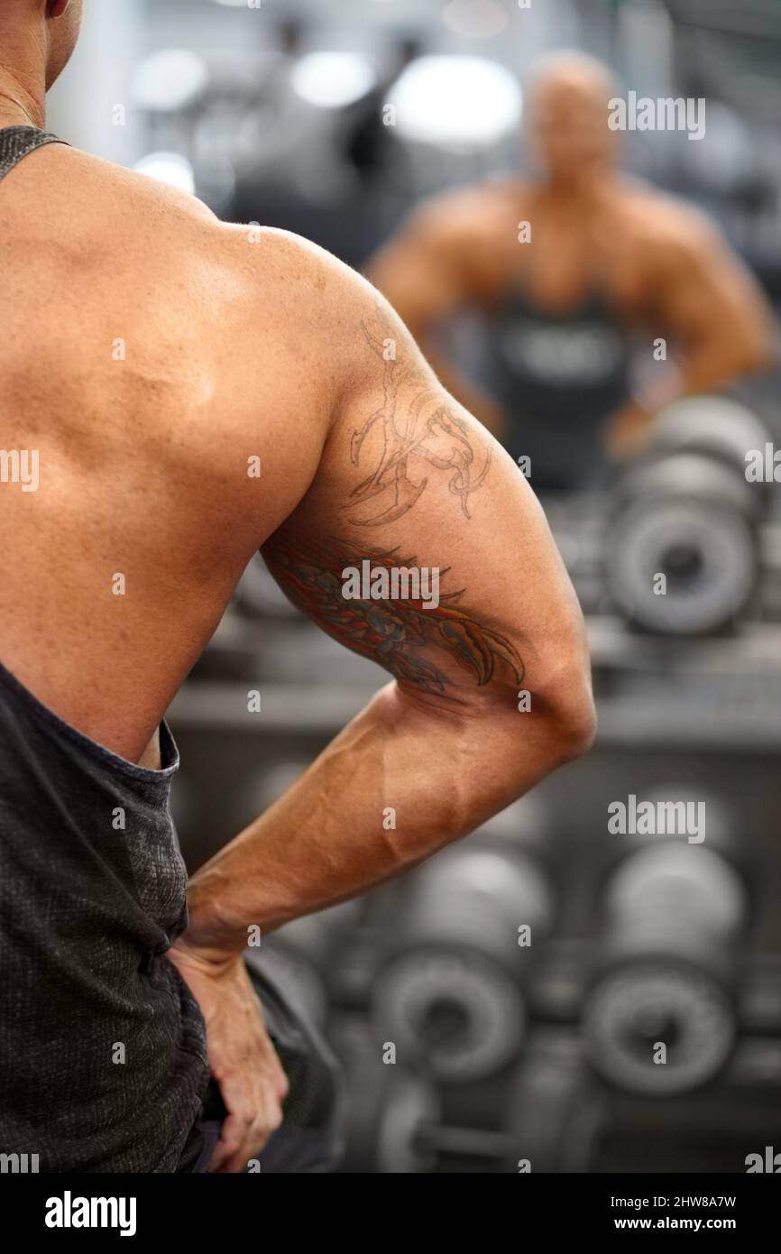 He is ripped. A muscular bodybuilder flexing his muscles while watching ...
