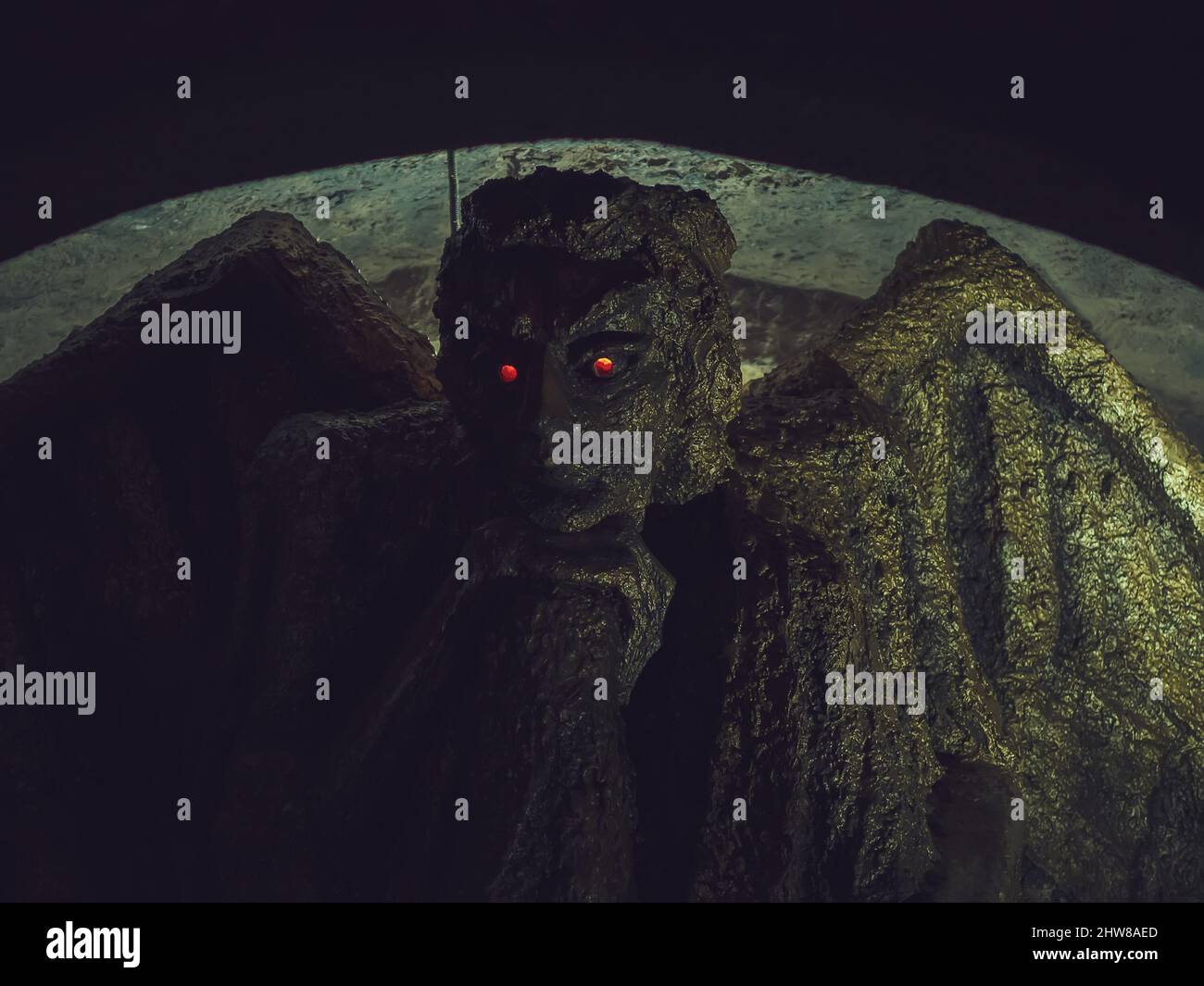 Russia, Kislovodsk 02.11.2021. A dark gilded statue of demon with red ...