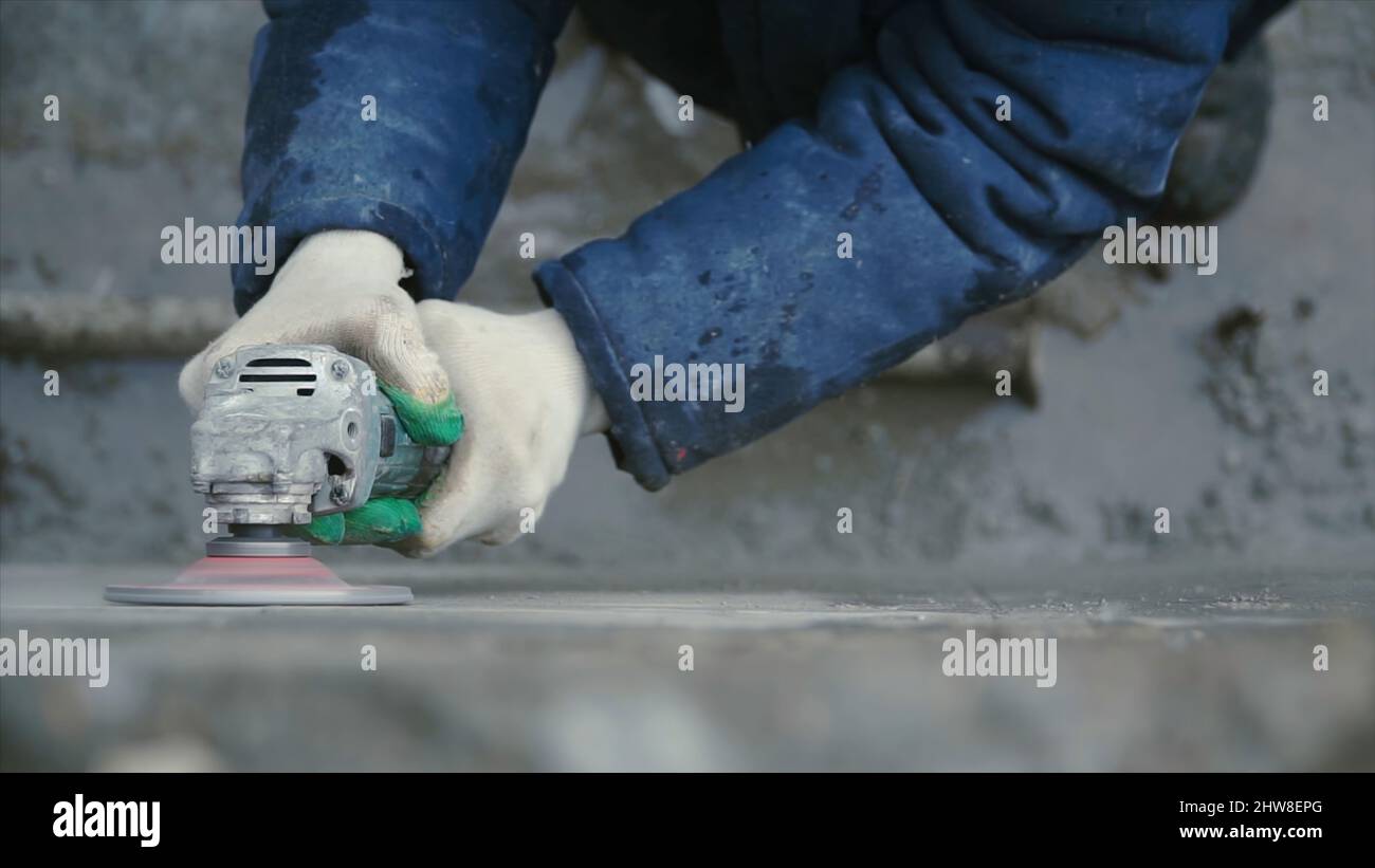 Builder worker with grinder machine cutting finishing concrete wall at ...