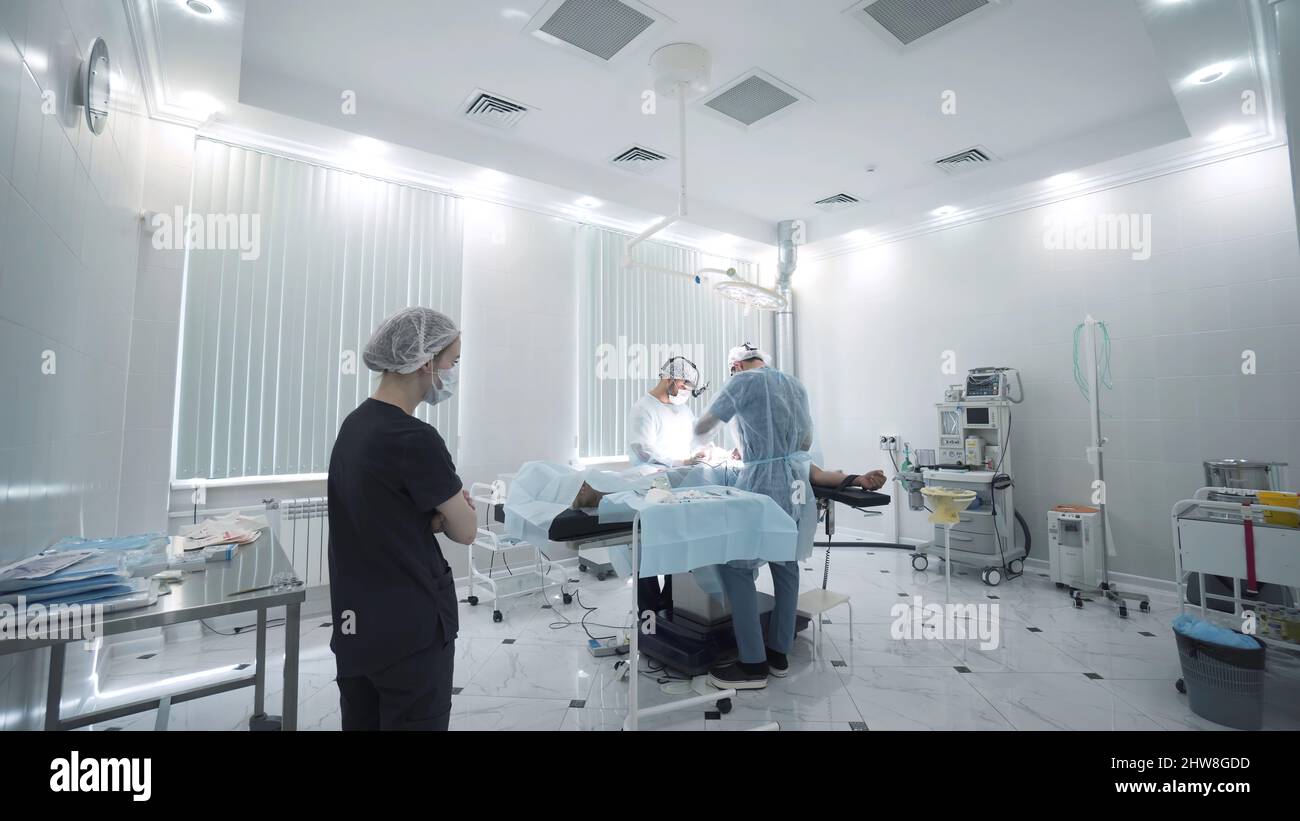 Team of surgeons and nurses during operation. Action. Nurse watches ...
