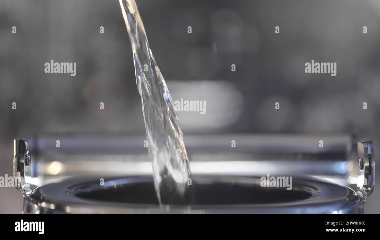 Close-up of water being poured into metal kettle. Action. Stream of clean water is poured into ...