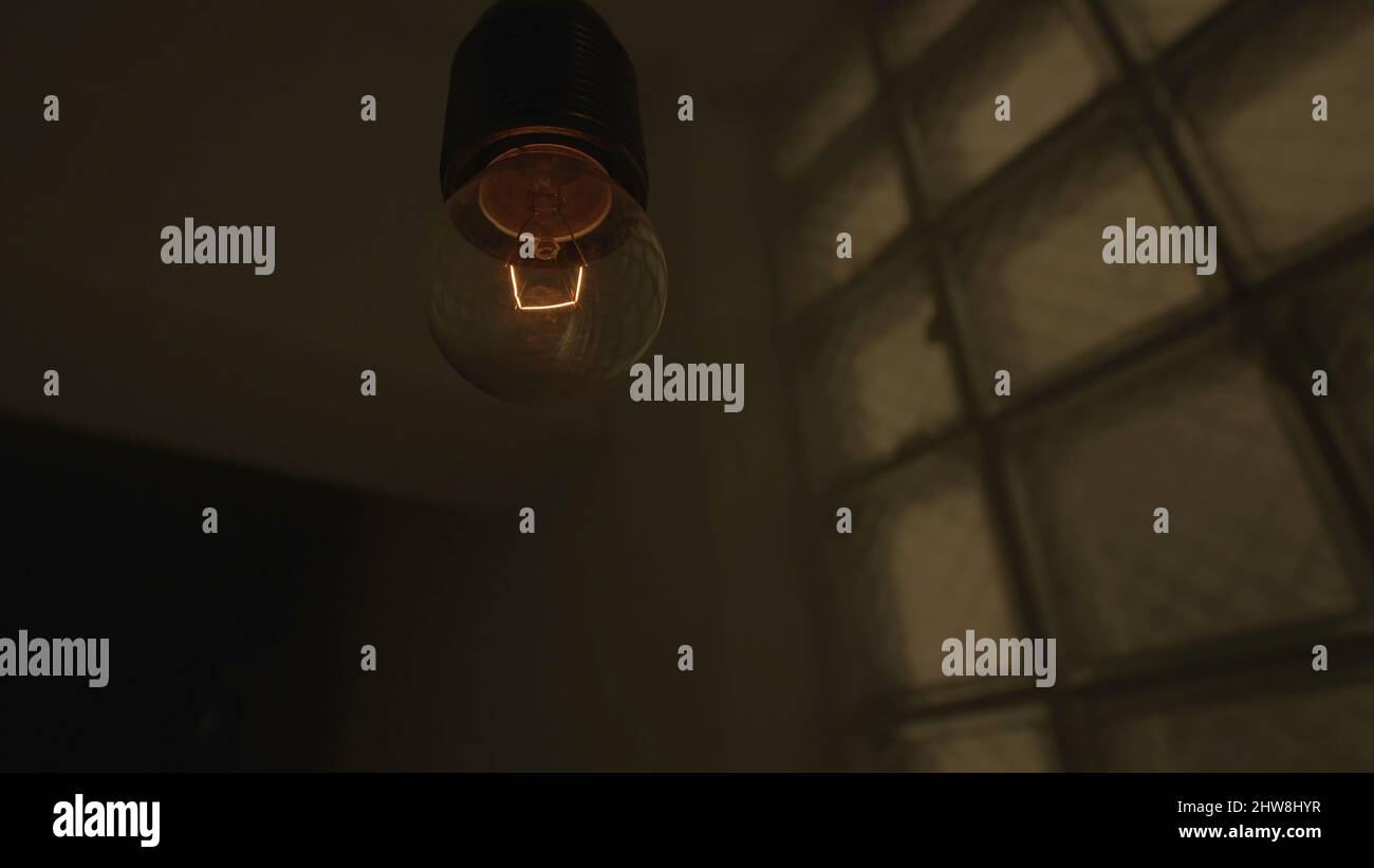Bottom view of a hanging swaying light bulb inside the entrance of a ...