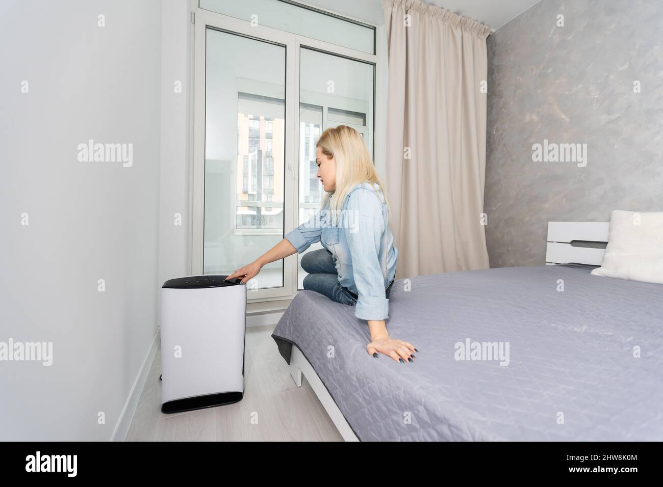 woman turning on and using the modern air purifier in the living room ...