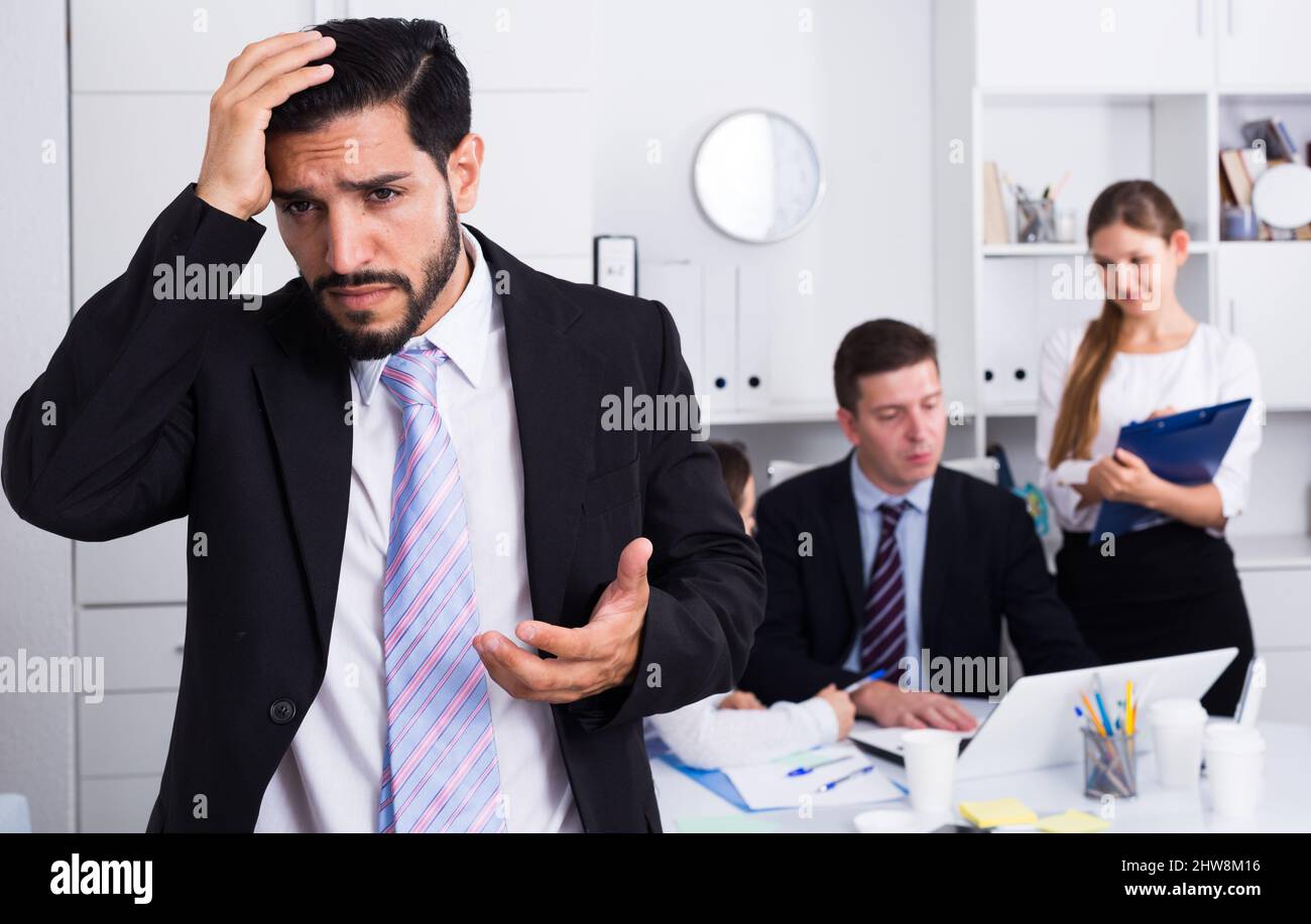Tired man at office with working colleagues Stock Photo - Alamy