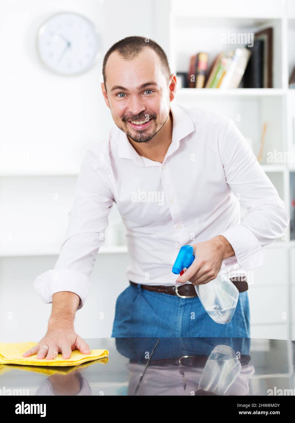Positive young man cleaning office desk Stock Photo - Alamy
