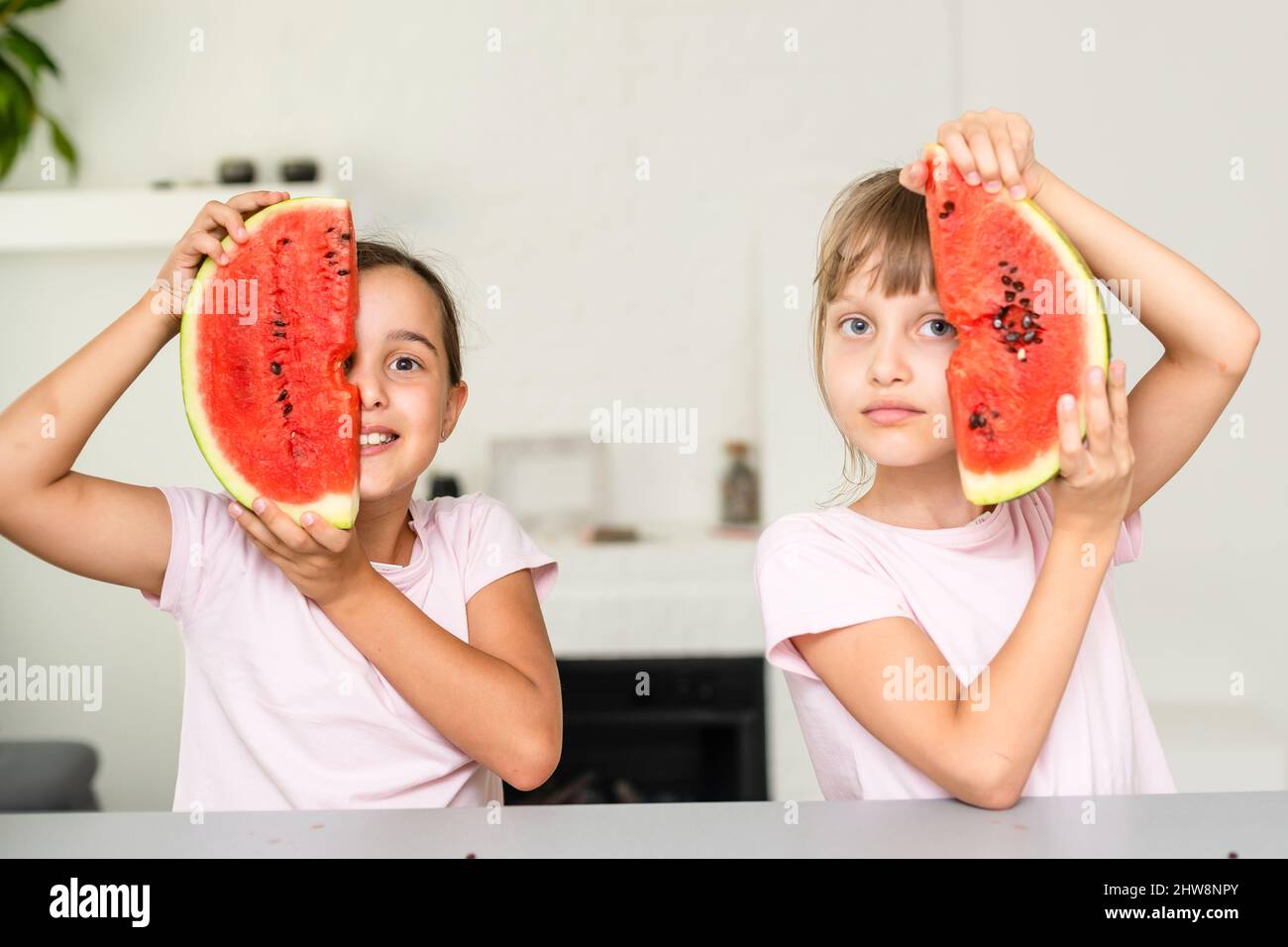 Two kids eating one slice of watermelon. Kids eat fruit outdoors ...