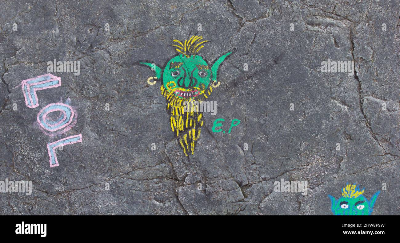 Chalk drawing of a green genie or sprite figure on a rock on Coverack ...