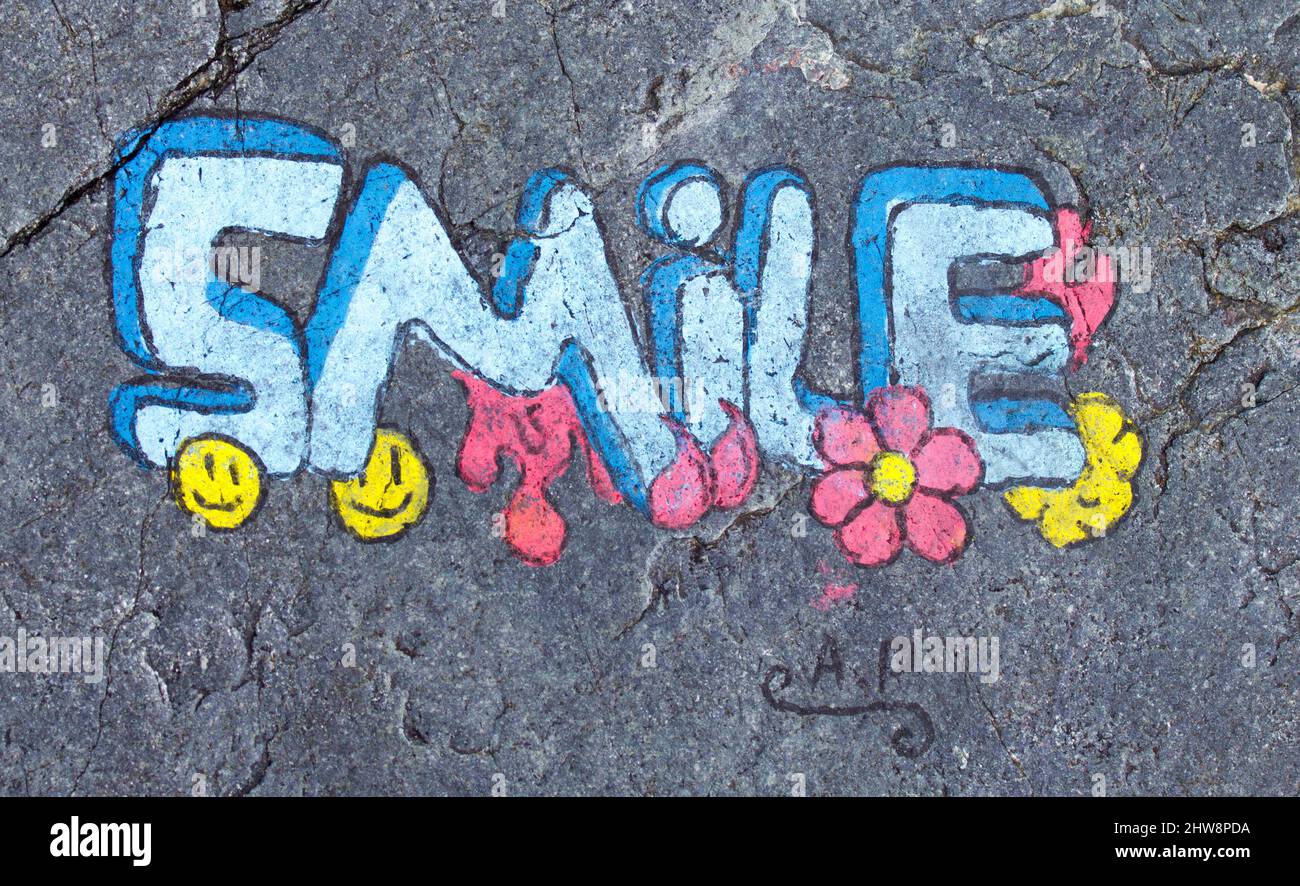Chalk drawing of the word SMILE on a rock on Coverack beach, Cornwall ...