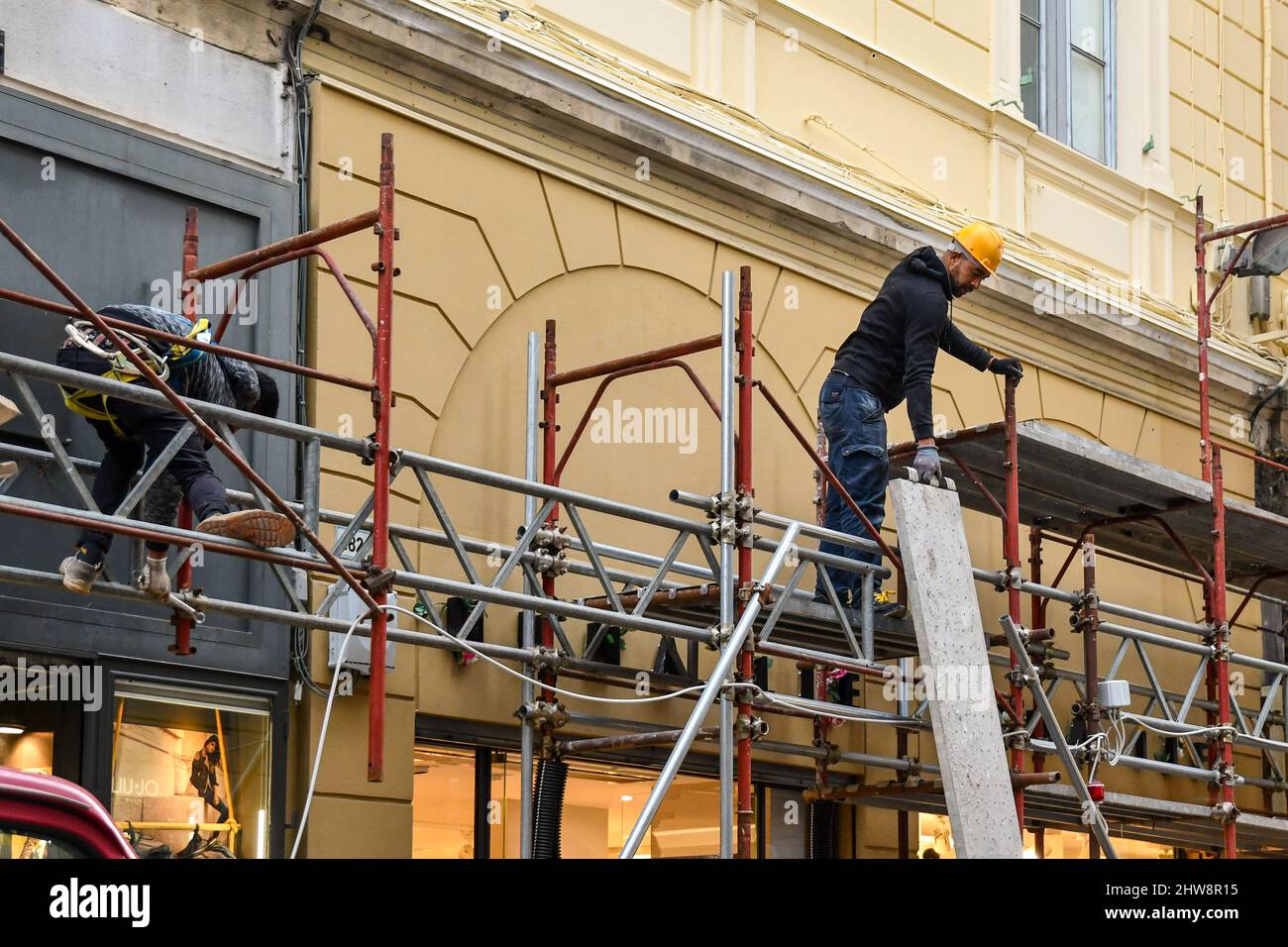 Two construction workers on a scaffold on the facade of a building ...