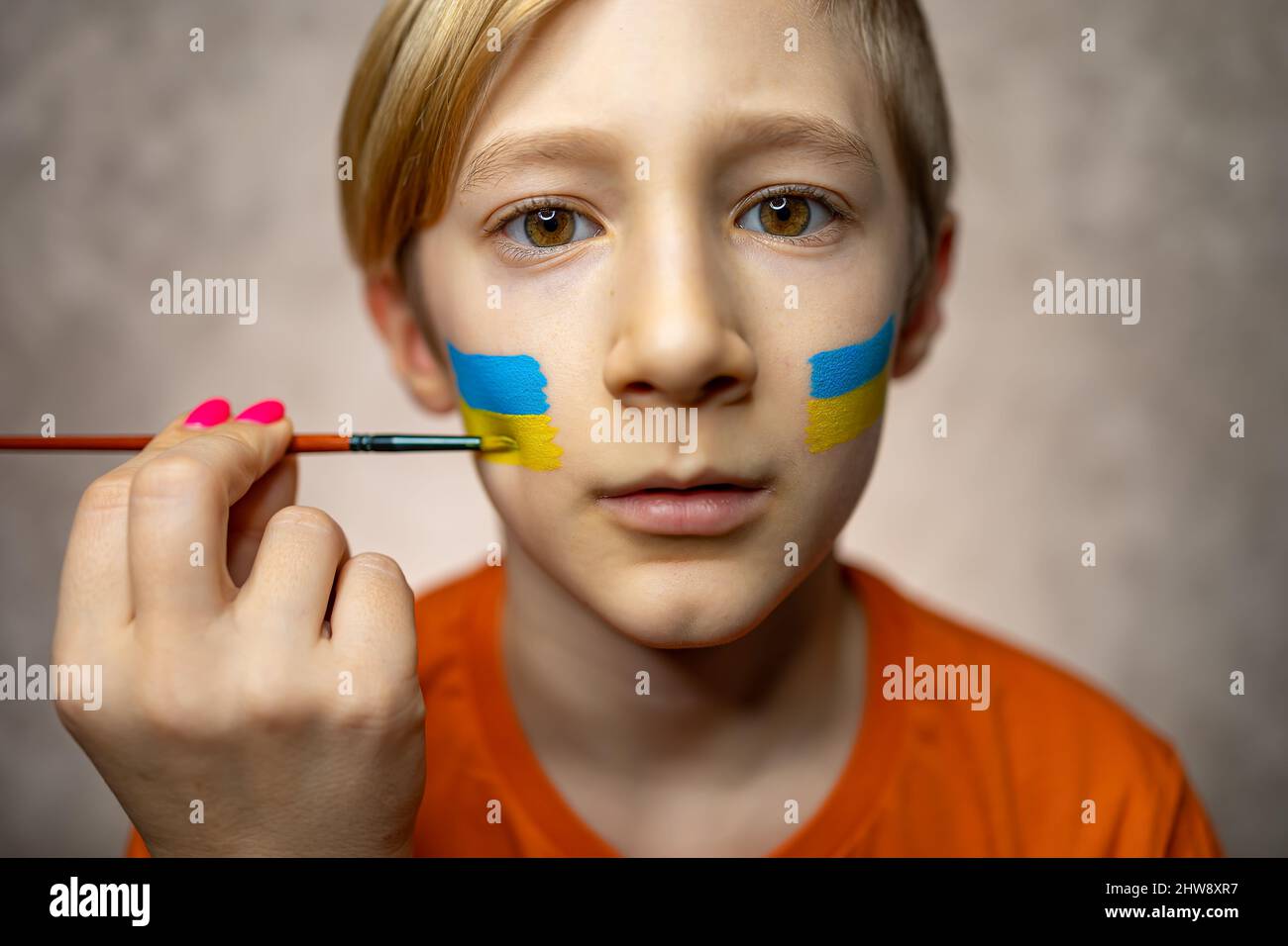 child against war, portrait of a boy with a painted flag of Ukraine on ...