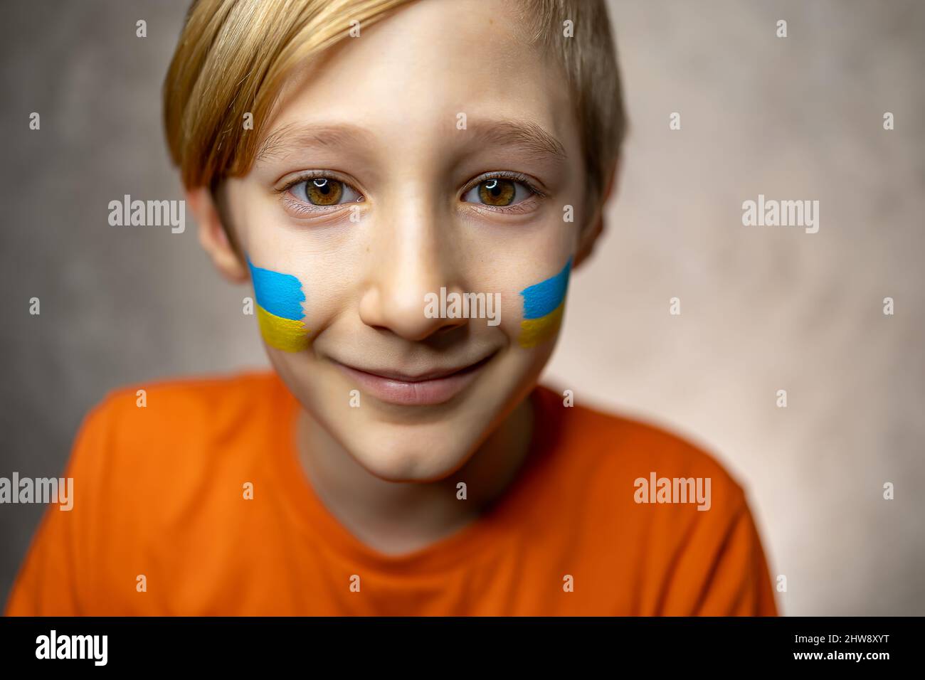 a child against war, a grinning boy with a painted flag of Ukraine on ...