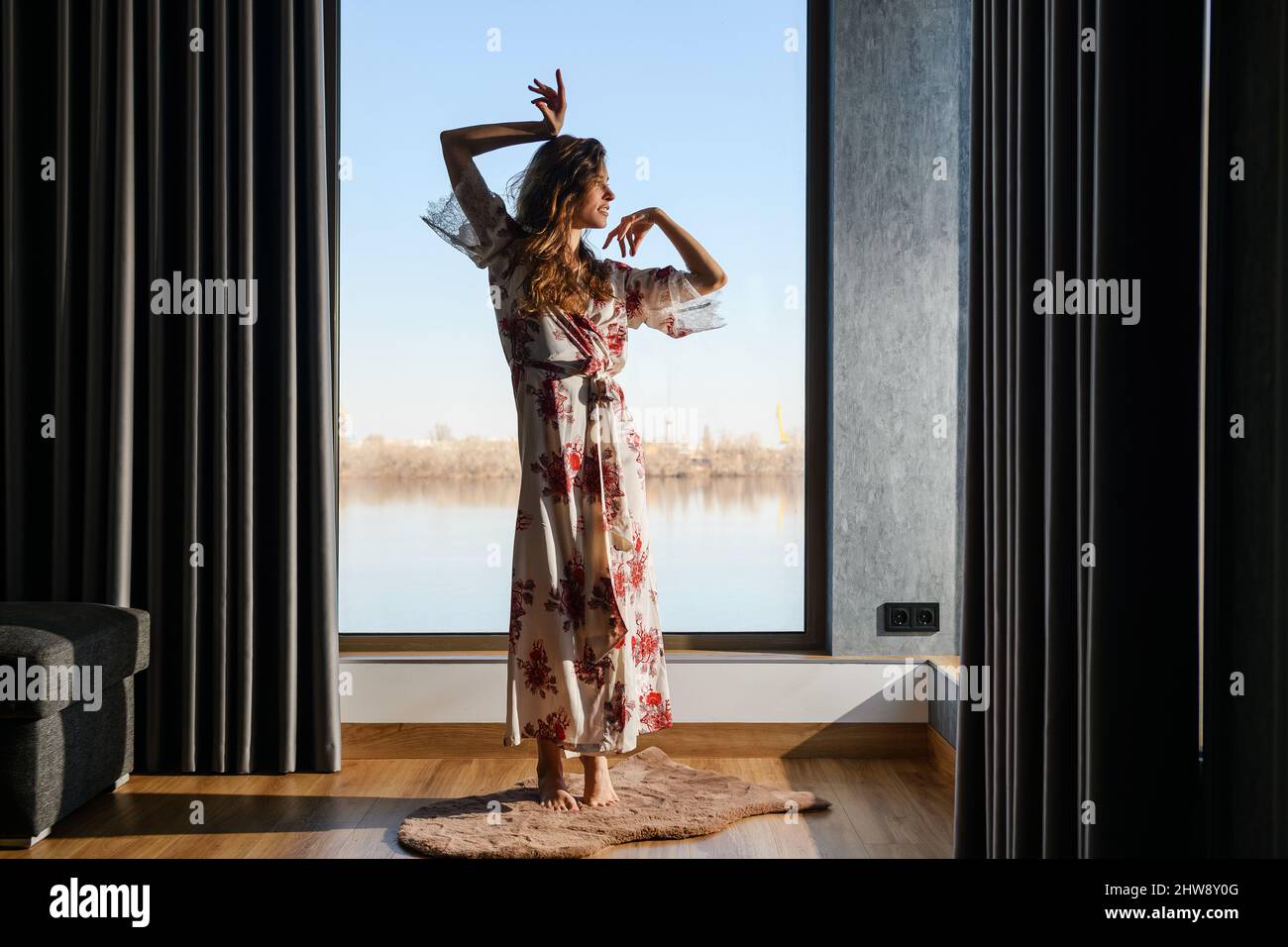 Attractive young woman dressed in a dressing gown dances in front of a ...