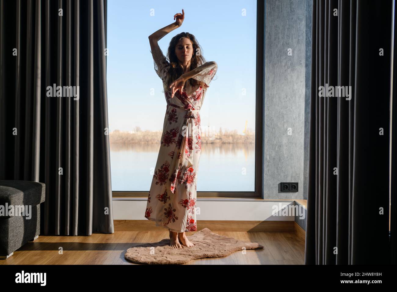 Attractive young woman dressed in a dressing gown dances in front of a ...