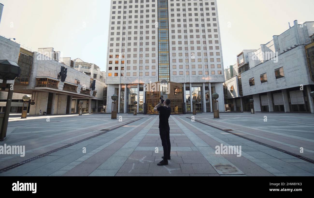 Man photographs beautiful modern building in city. Action. Professional ...