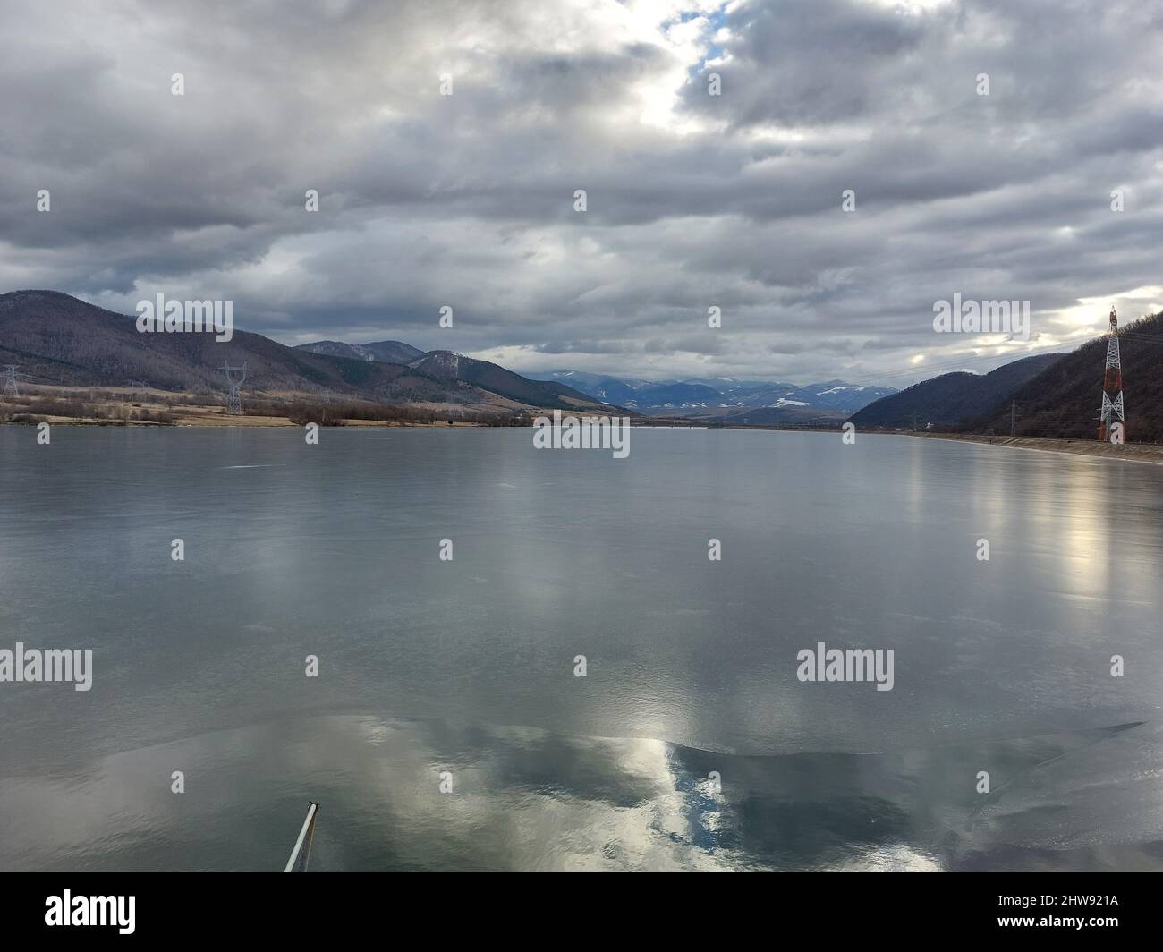 View of the frozen Strei river dam with mountains and clouds on the ...