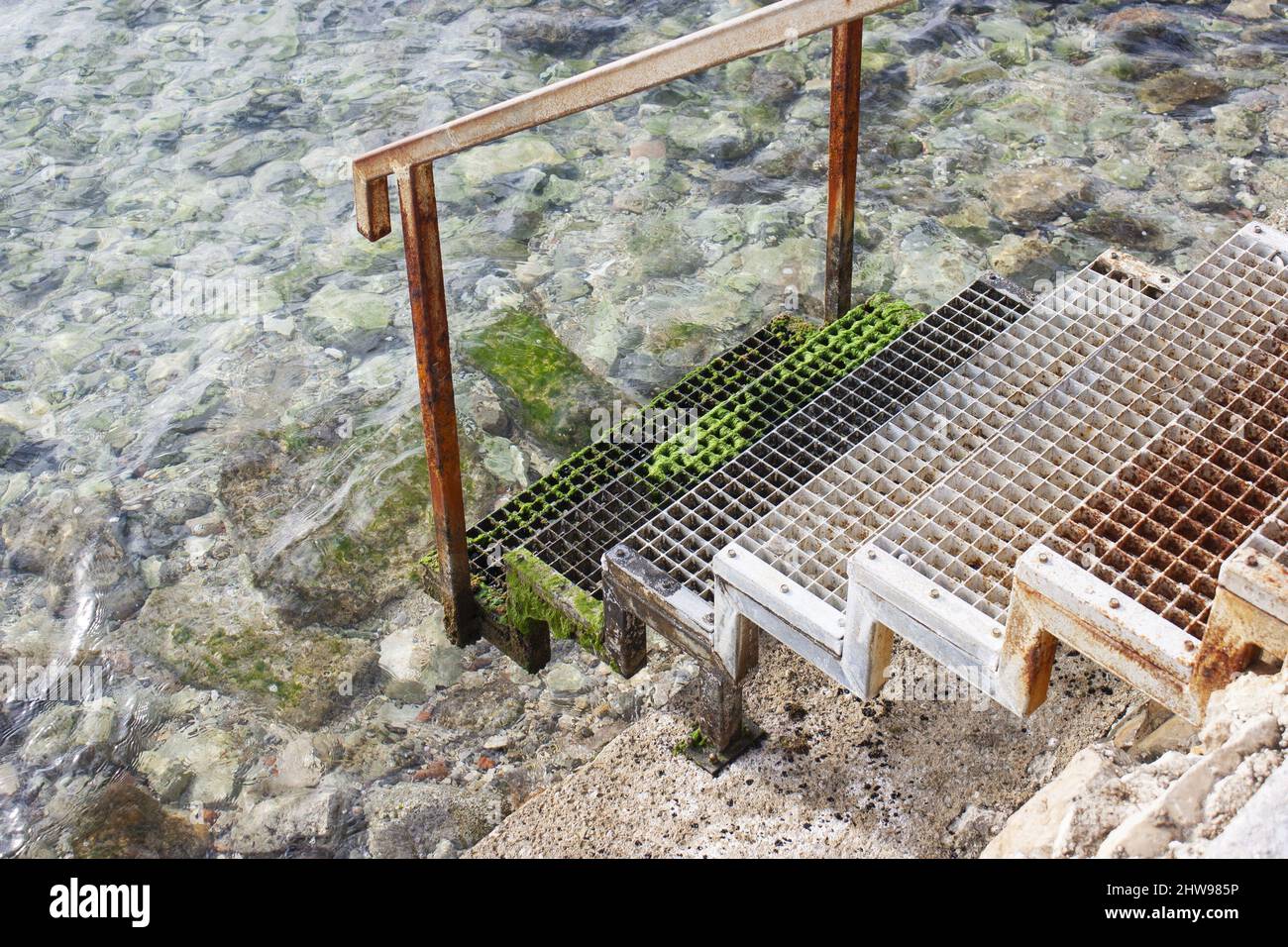 Closeup shot of the metal stairs leading to the sea with overgrown ...