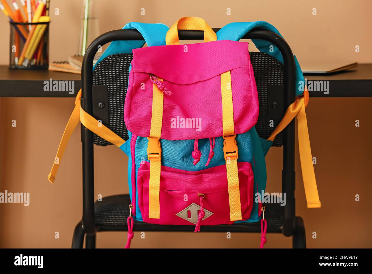 Stylish backpack hanging on chair in room Stock Photo - Alamy