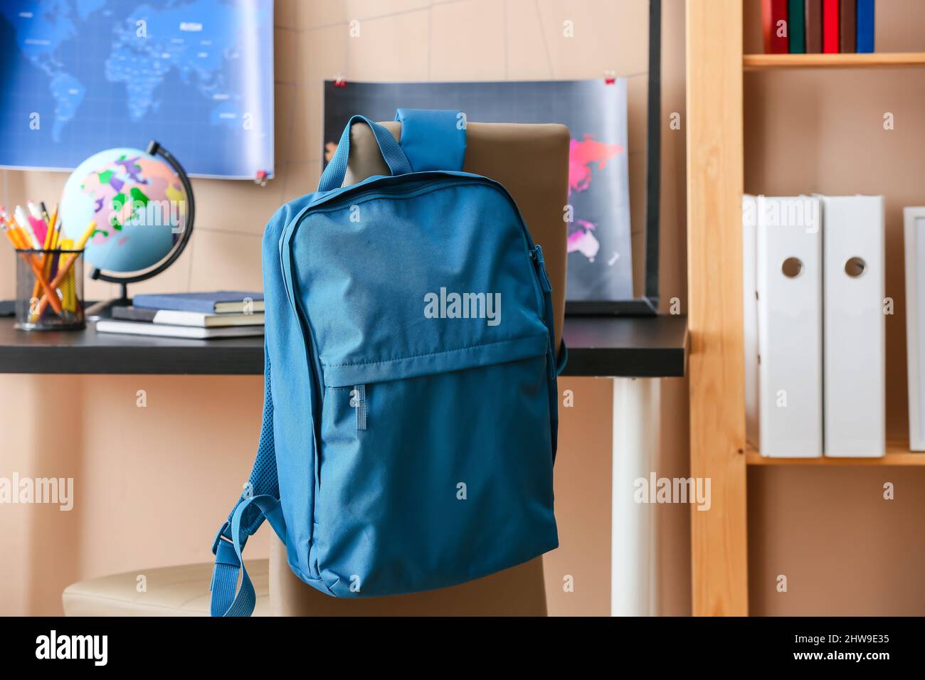 Stylish backpack hanging on chair in room Stock Photo - Alamy