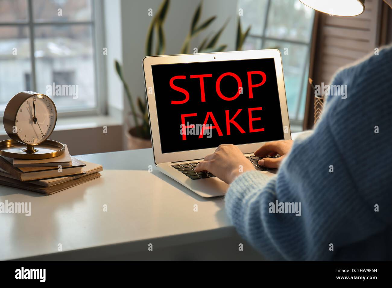 Woman using laptop with text STOP FAKE on screen Stock Photo - Alamy
