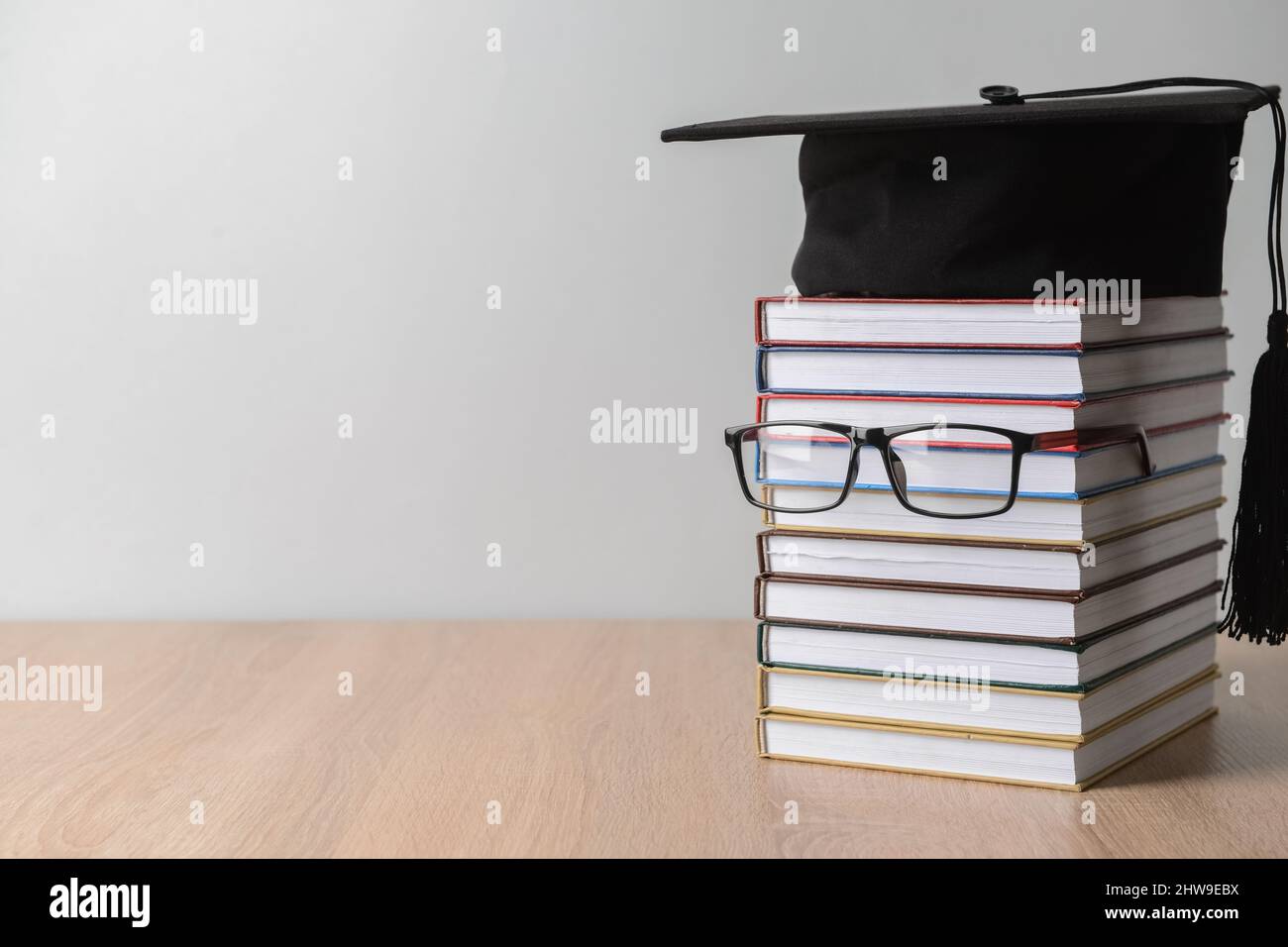 Creative composition with books, eyeglasses and graduation hat on table ...