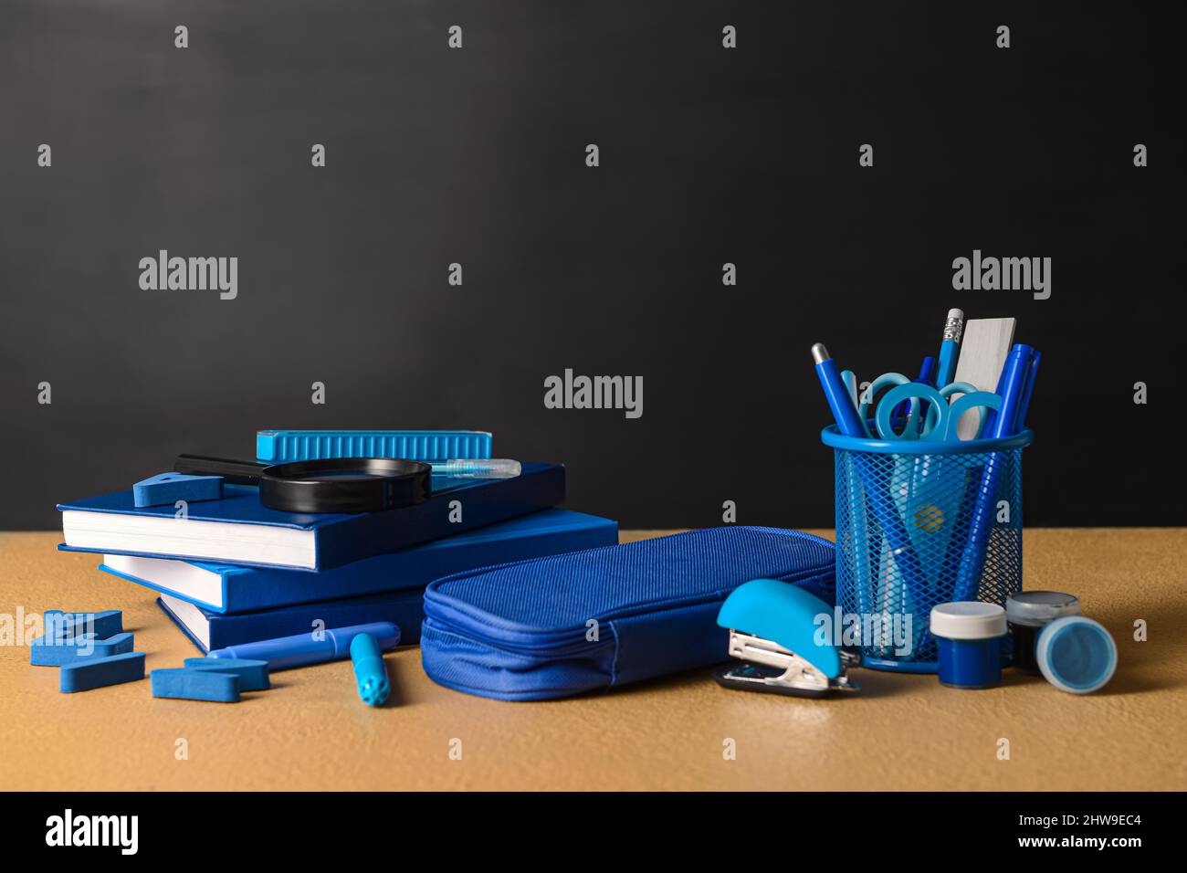 Set of colorful stationery with magnifier on table against dark ...