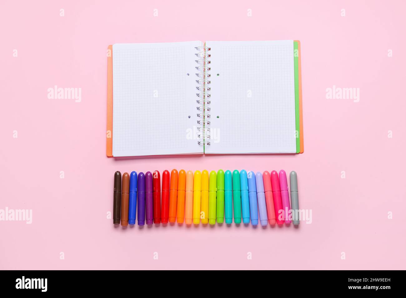 Blank open notebook and markers on pink background Stock Photo - Alamy