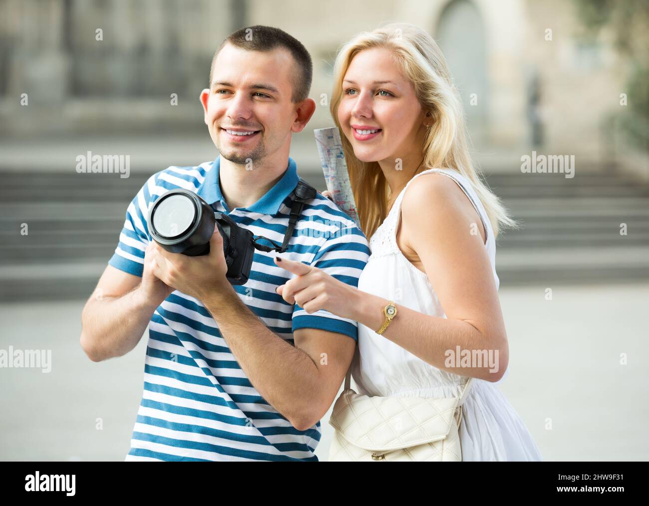 Two smiling tourists photographing in city Stock Photo - Alamy